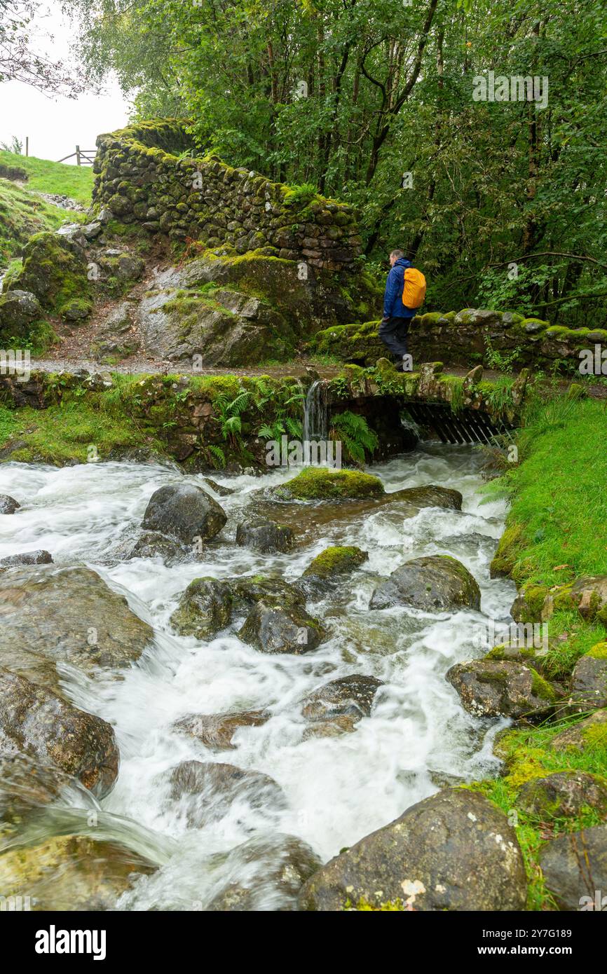 A walker on a wet day crossing Jubilee Bridge over the River Esk ...