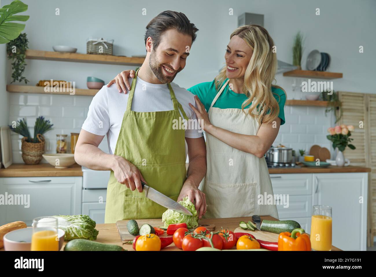 Beautiful young couple cooking together and bonding at the domestic ...