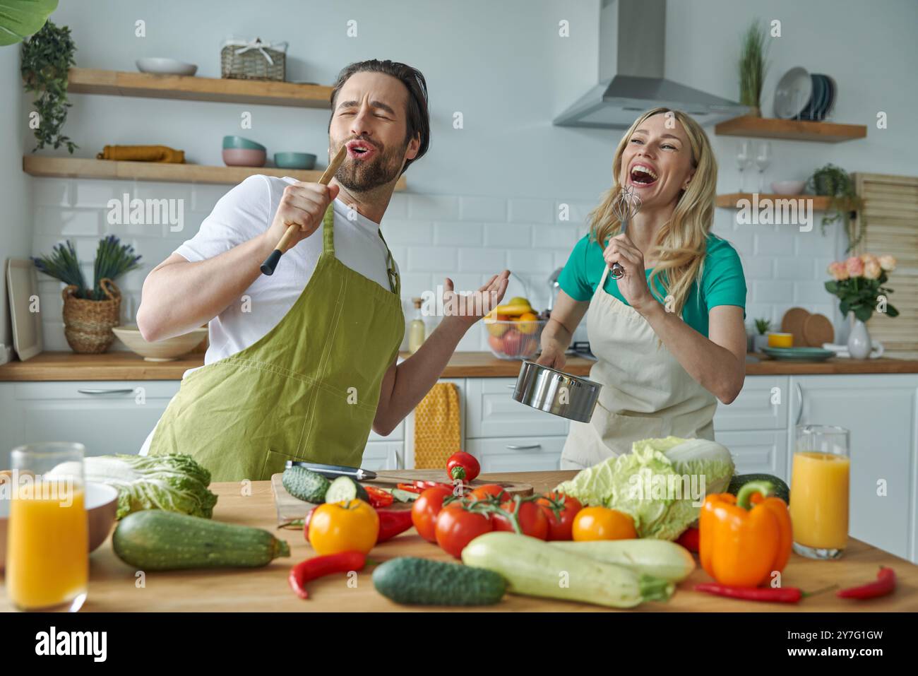 Playful young couple having fun while cooking together at the kitchen ...
