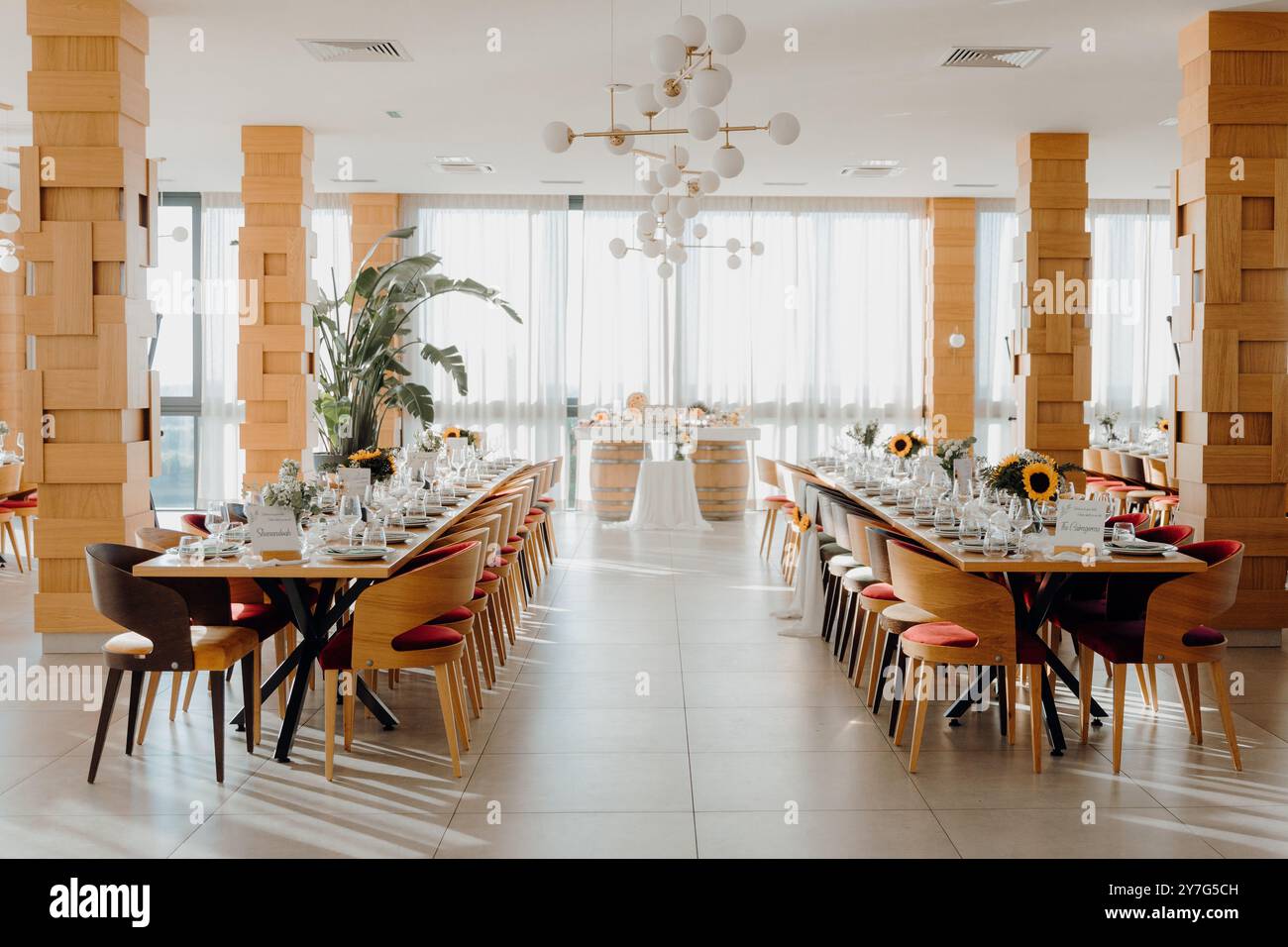 A modern restaurant interior with long tables set for a formal event ...