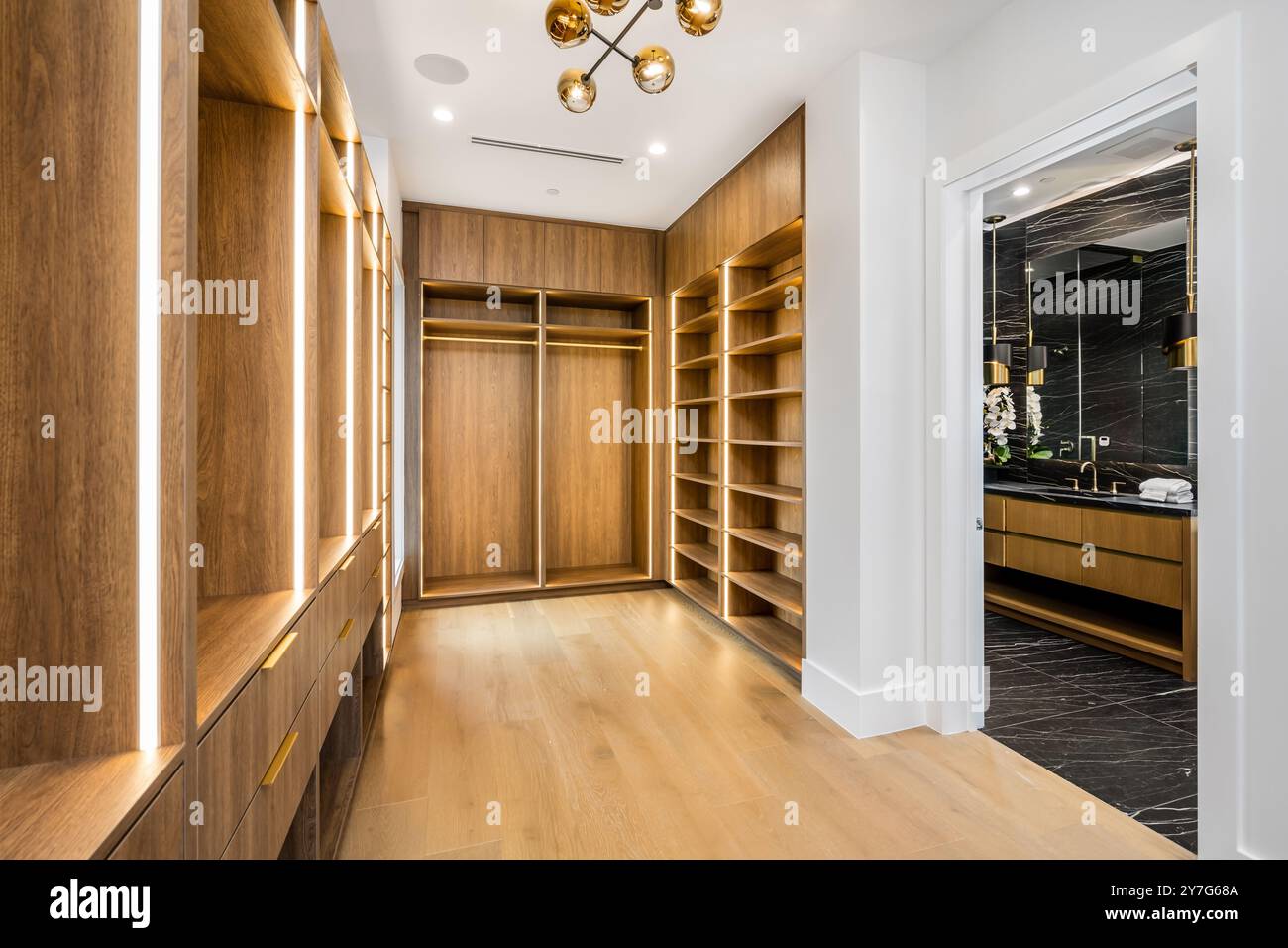 Modern walk-in closet with wooden shelves and drawers, leading to a ...
