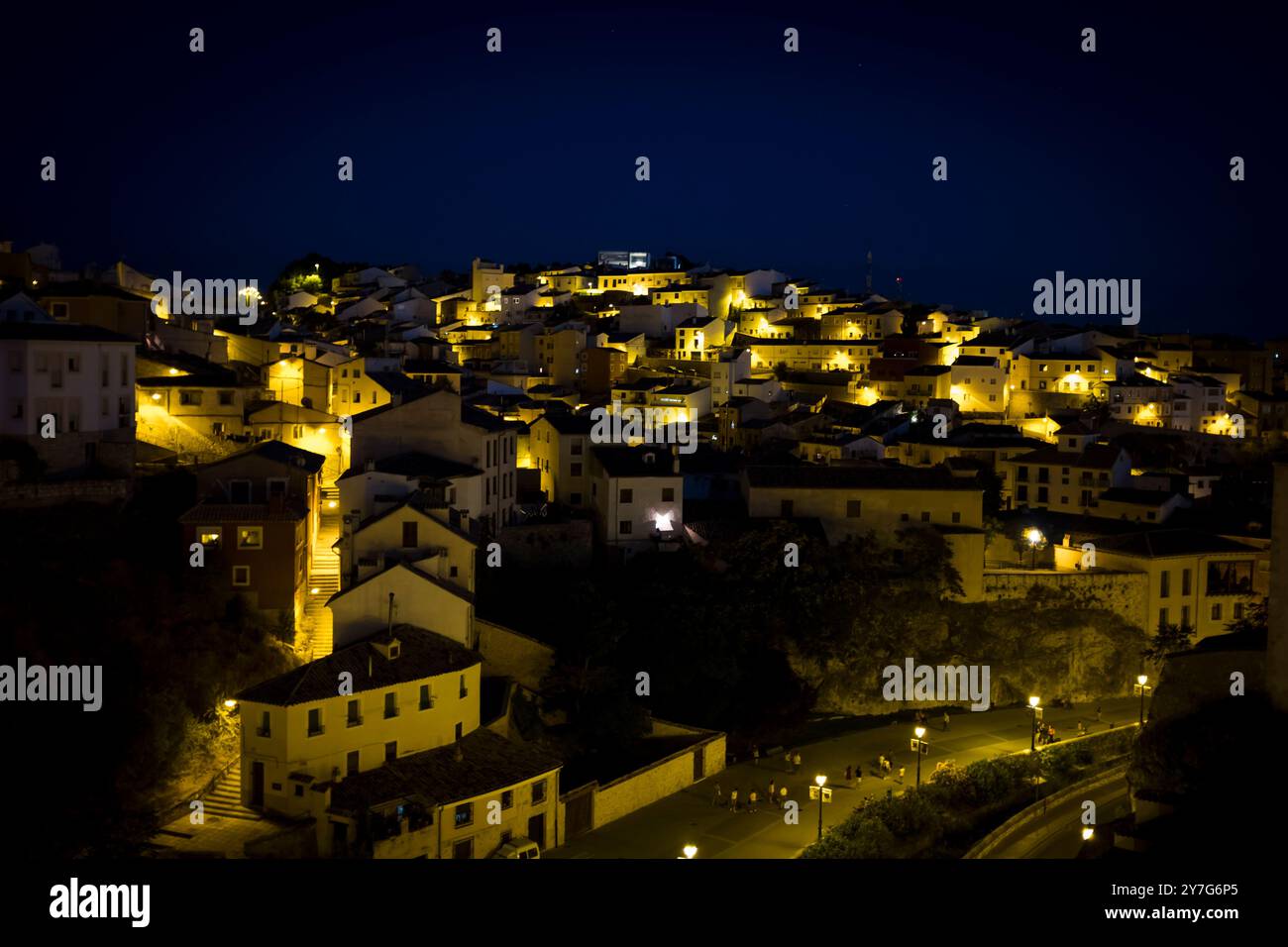 A night view of a hillside town with illuminated houses and a clear ...