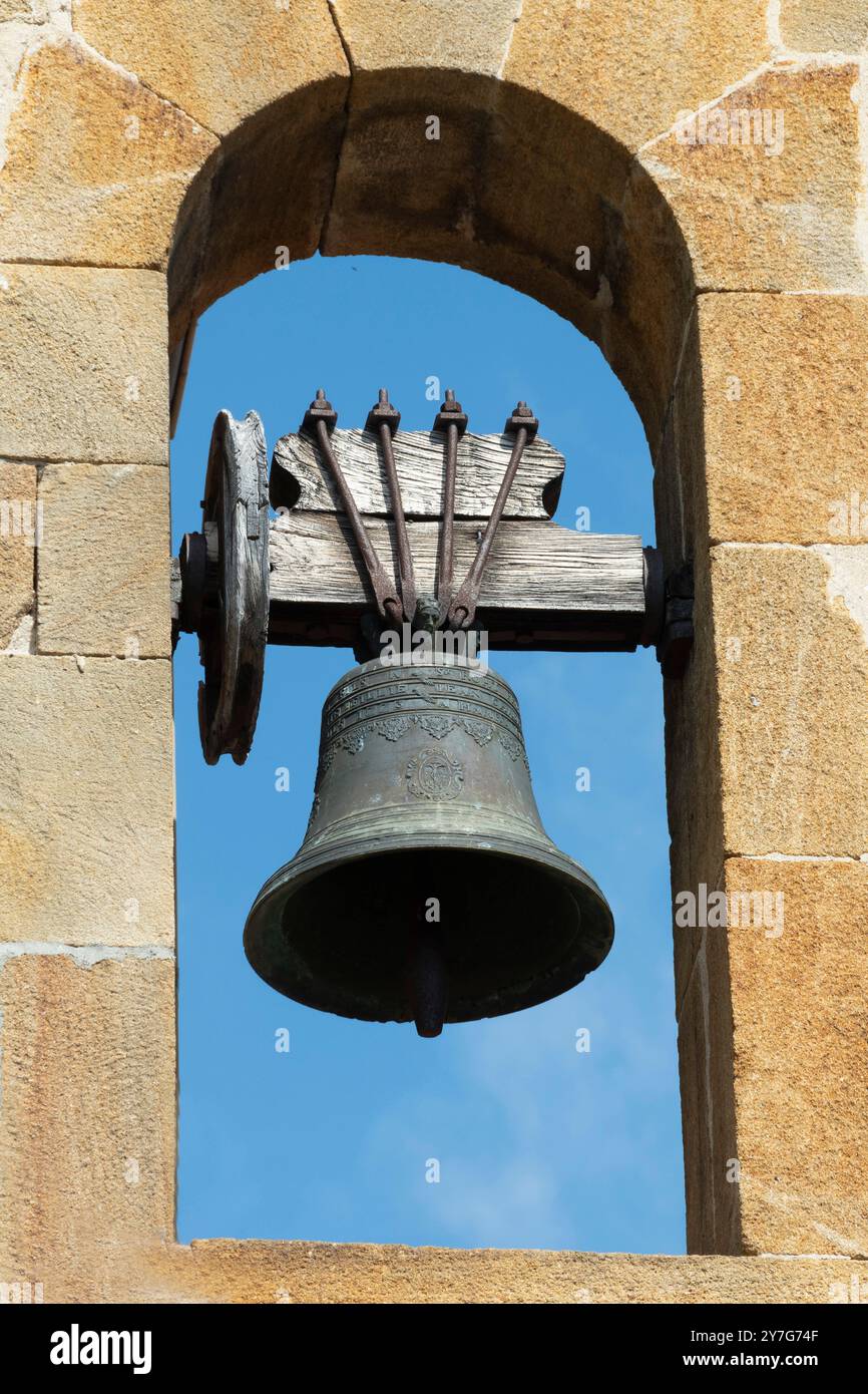 Bell hanging in a stone tower against a bright blue sky captured during daylight hours Stock ...