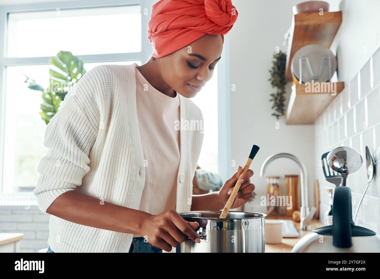 Beautiful African woman mixing something in pan while preparing food at ...