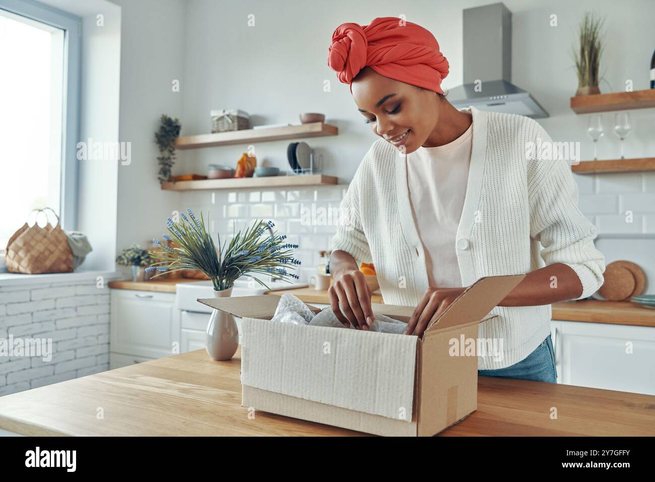 Curious African woman unpacking box while standing at the domestic ...