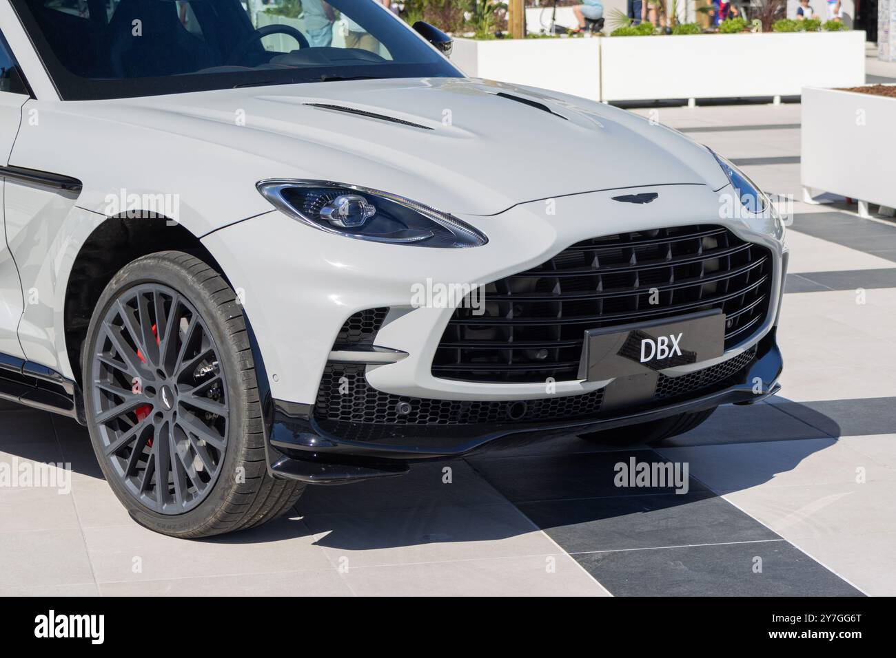 White aston martin dbx parked on a city street with pedestrians walking ...