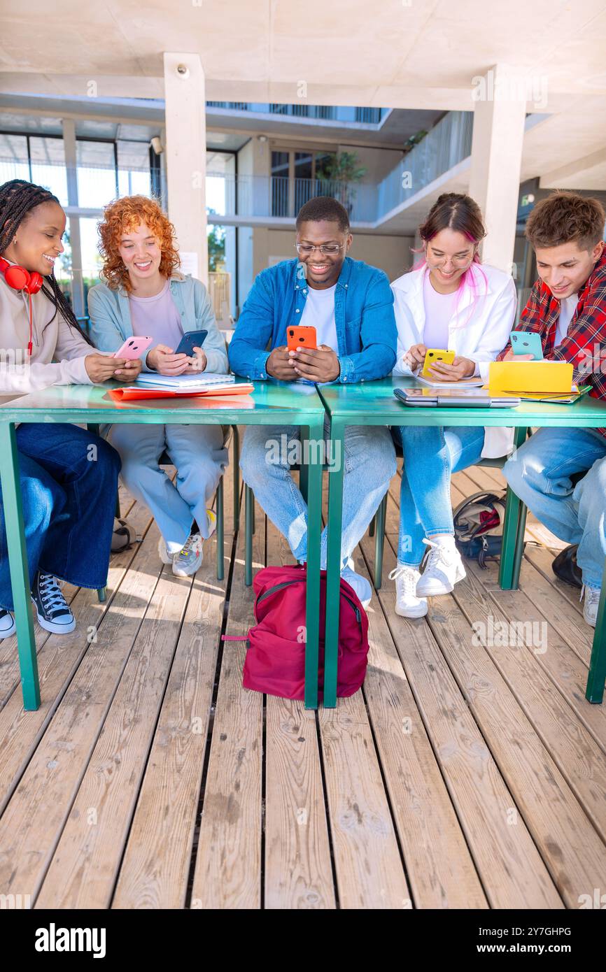 Five happy multiracial students studying with smartphones outdoors ...