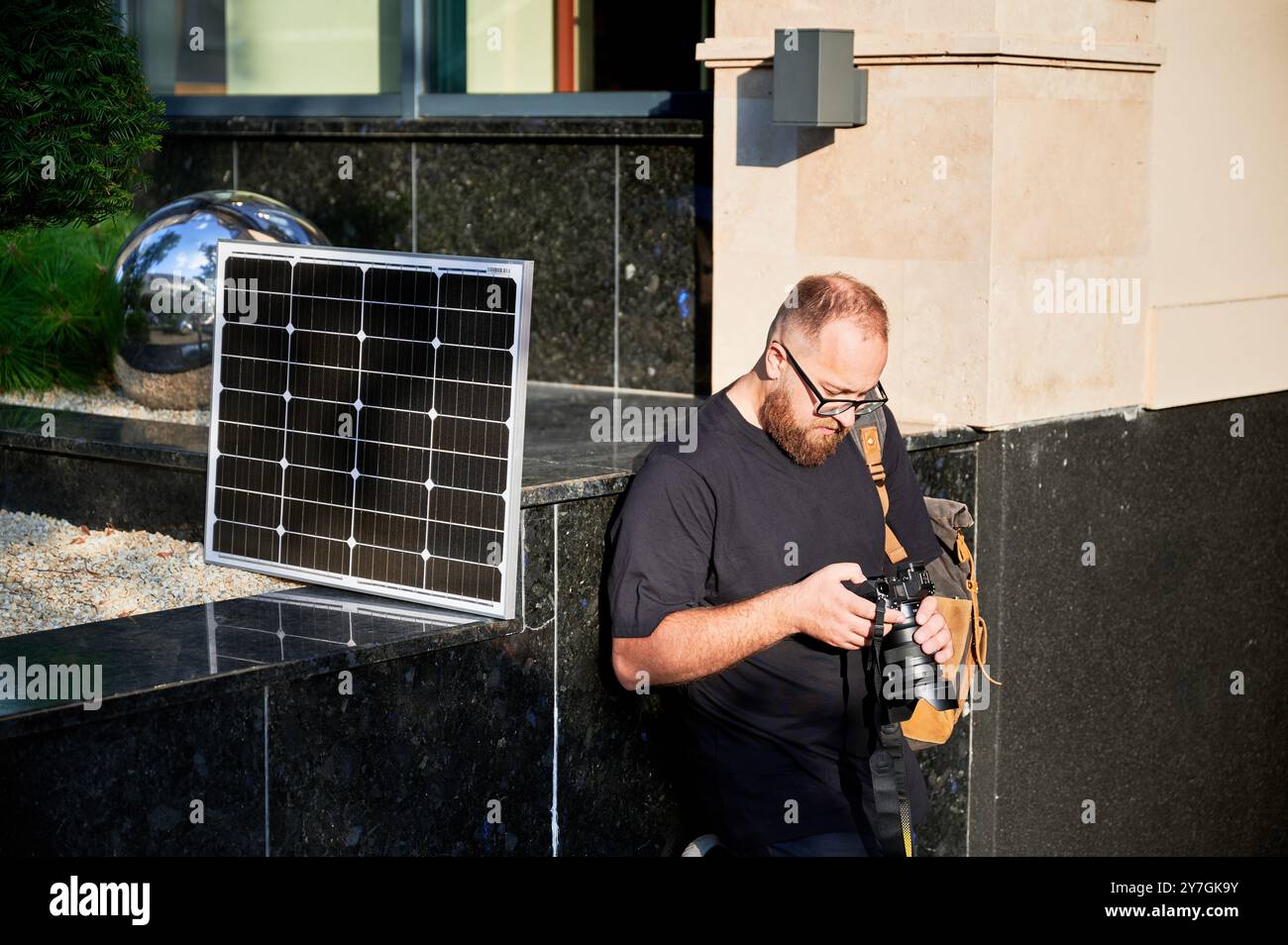 Bearded male photographer reviewing photos on camera, with solar panel ...