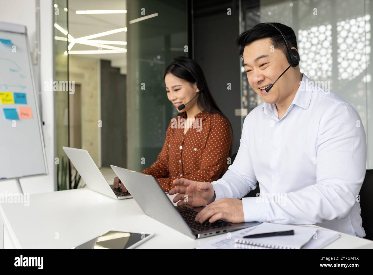 Smiling customer service team in modern office using laptops and ...