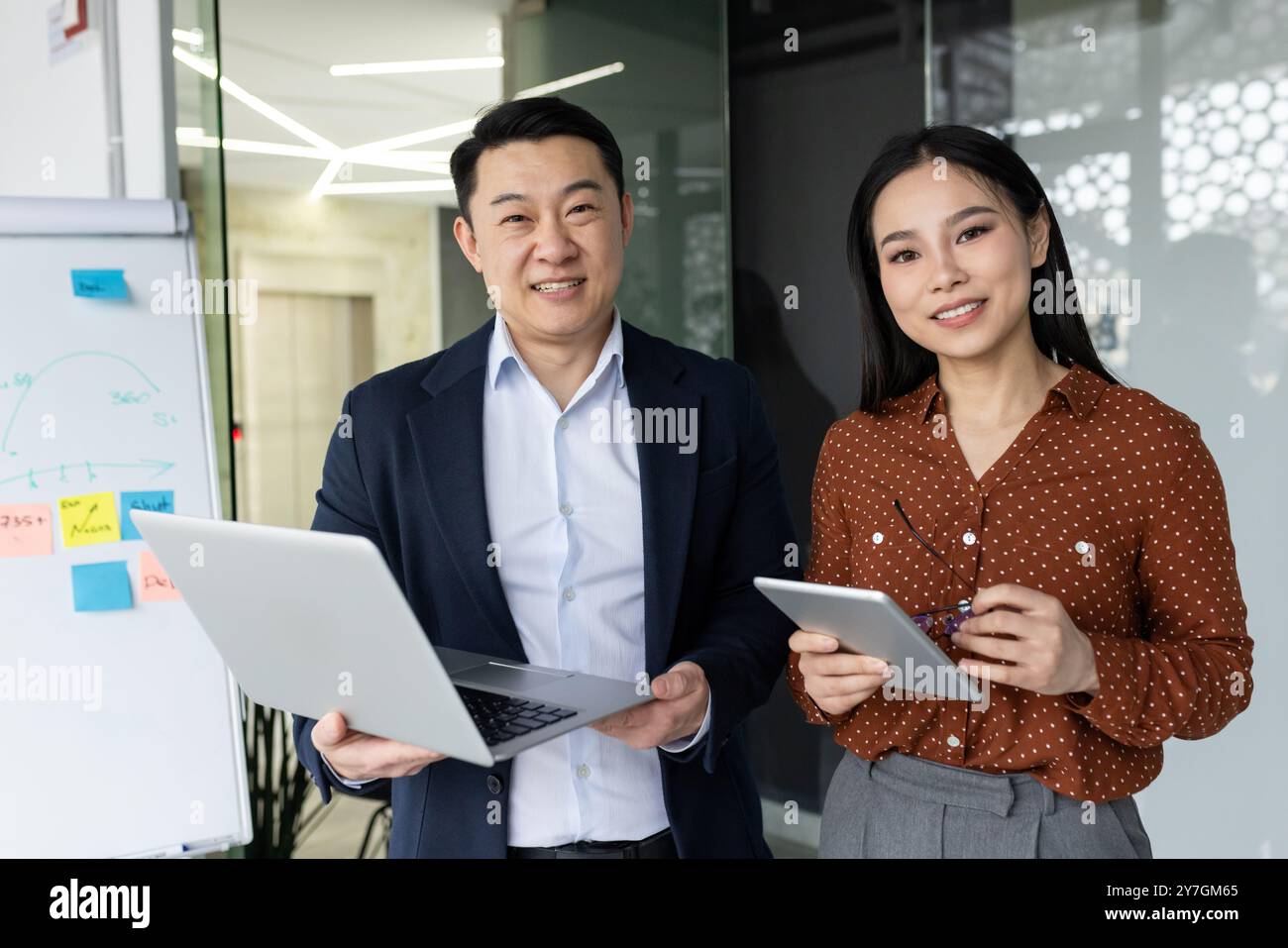 Business professionals engaged in teamwork holding laptop and tablet in ...