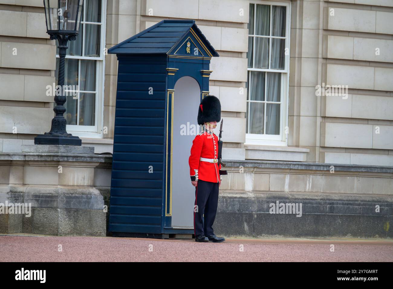 A traditional British guard stands stoically in front of a historic ...