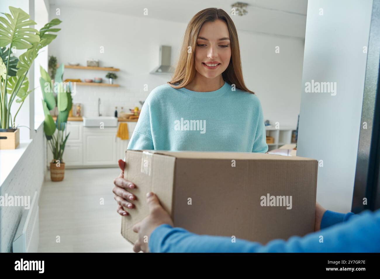 Beautiful young woman accepting box from delivery man at home Stock ...