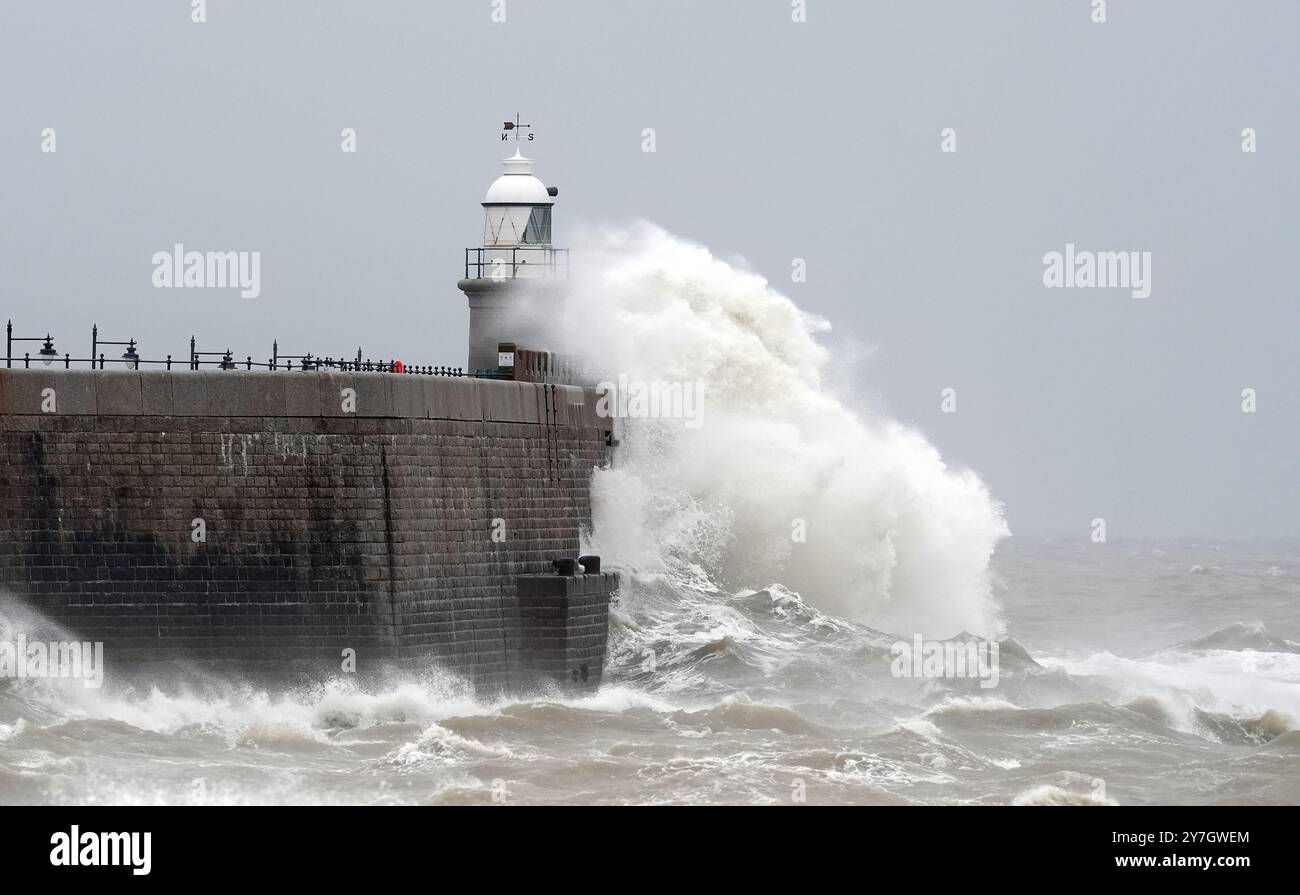 Waves crash against the harbour wall during wet and windy weather in ...
