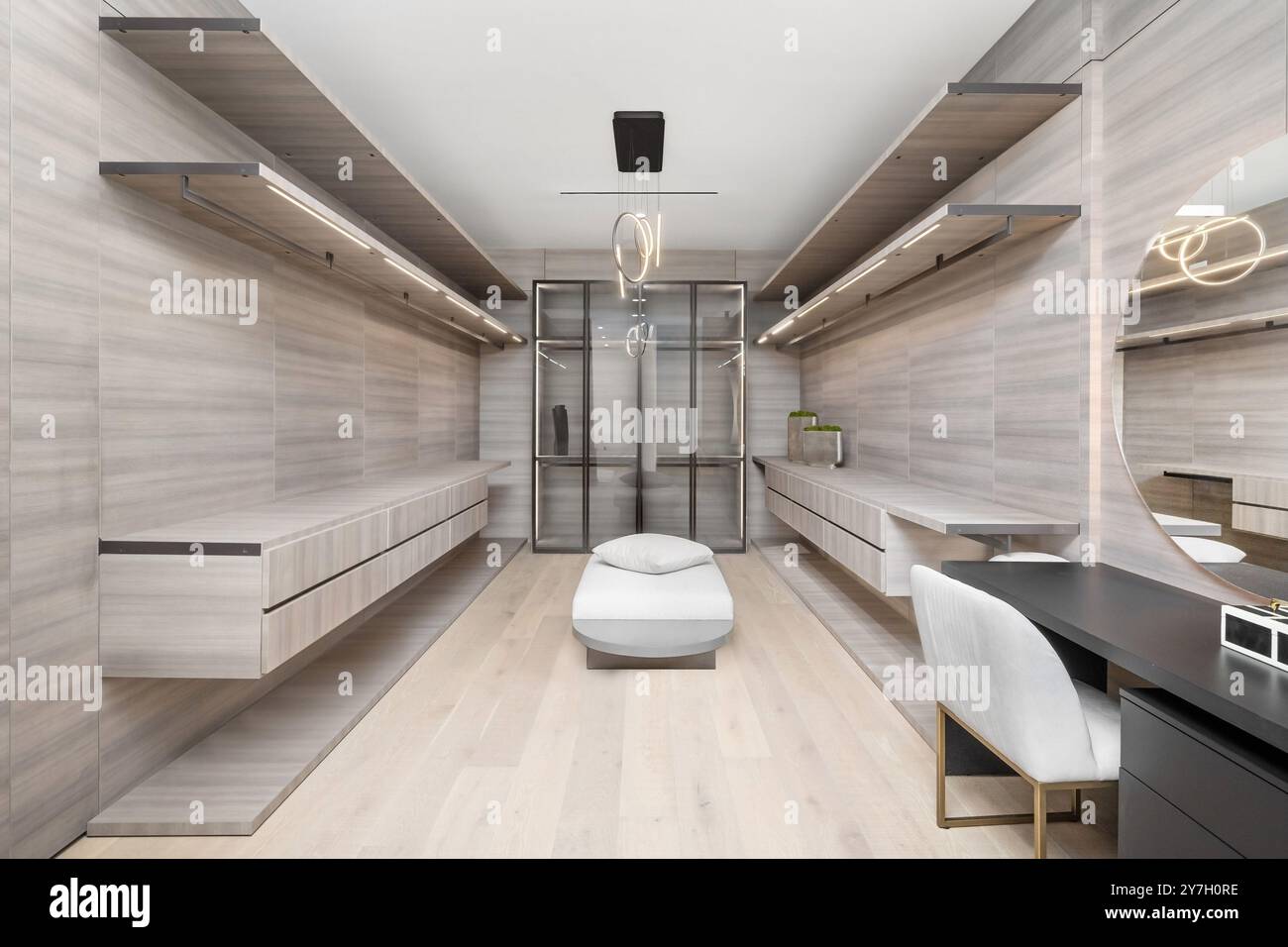 Modern walk-in closet with built-in shelves, a vanity table, and a ...