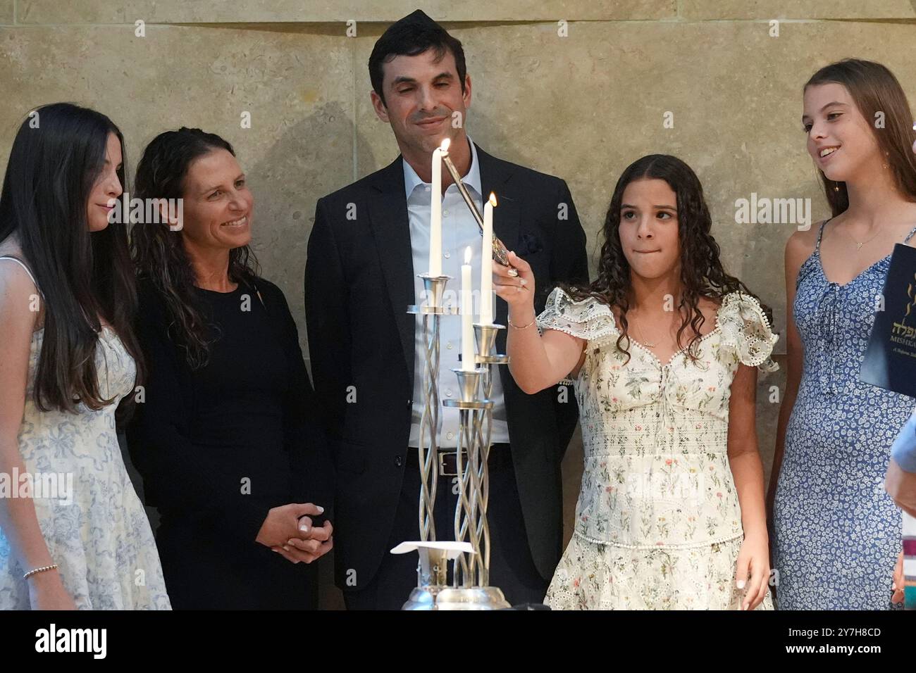 Quinn Schimel, second from left, lights a Shabbat candle as she stands ...
