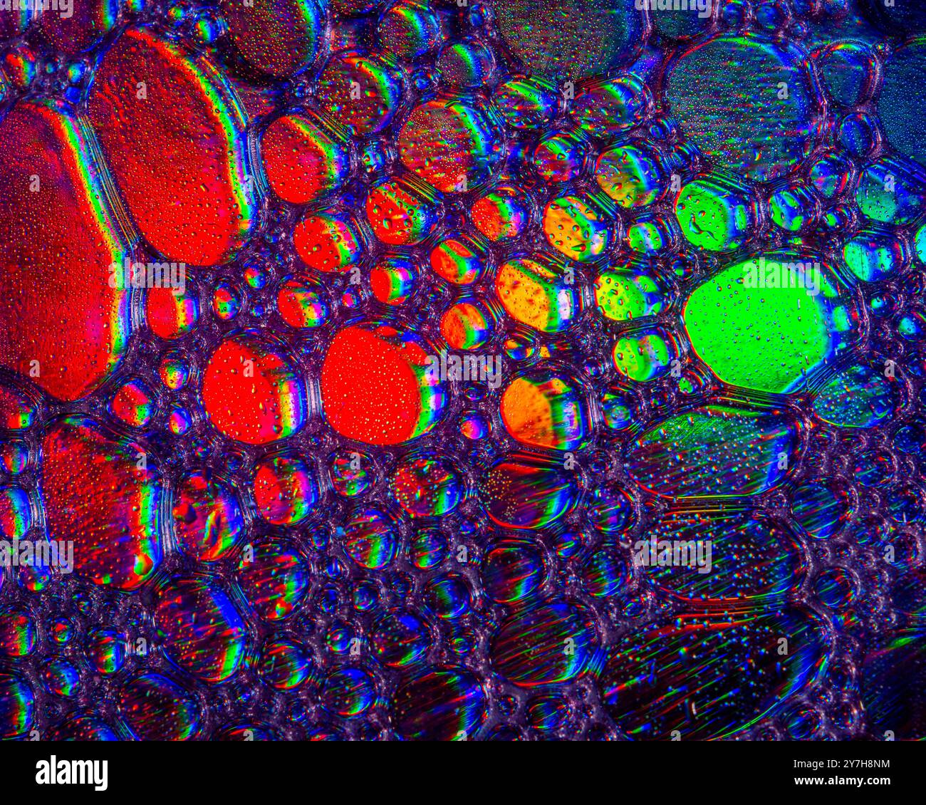 A macro shot showing patterns and colours of oil drops floating on a ...