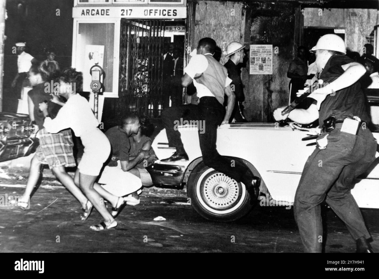 Black rioters dash out of the way of night-stick wielding cop during ...