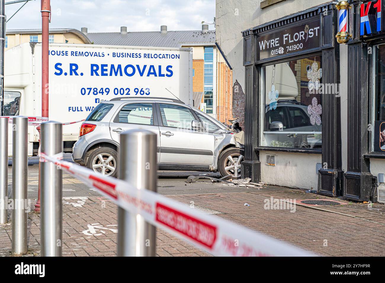 Side view of a small car crashed into the entrance of a high street ...