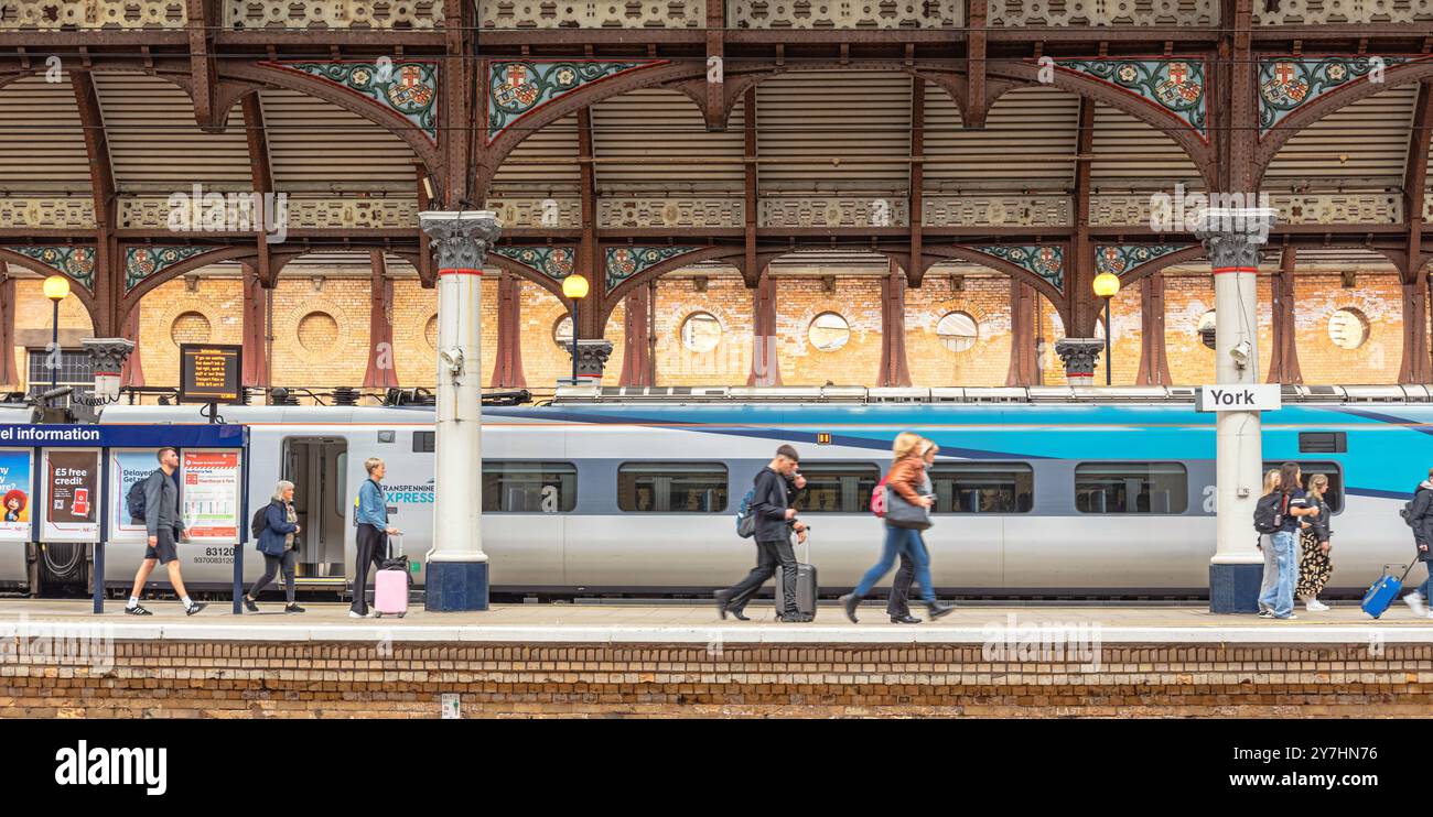 A modern train stands at a historic railway station platform under a ...