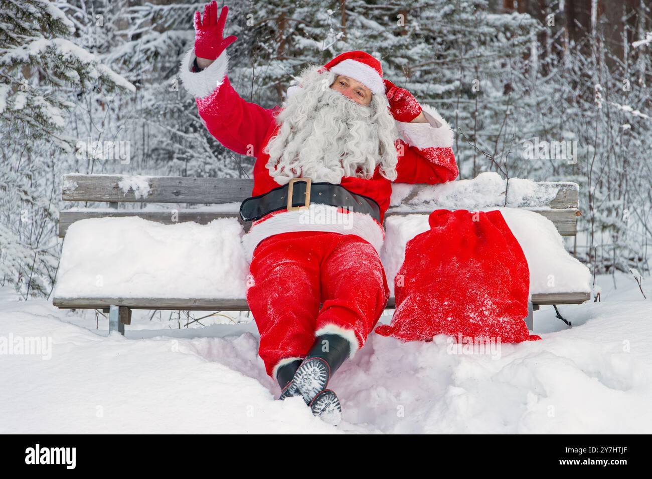Santa Claus sitting on a snowy bench and waving hand to camera Stock ...