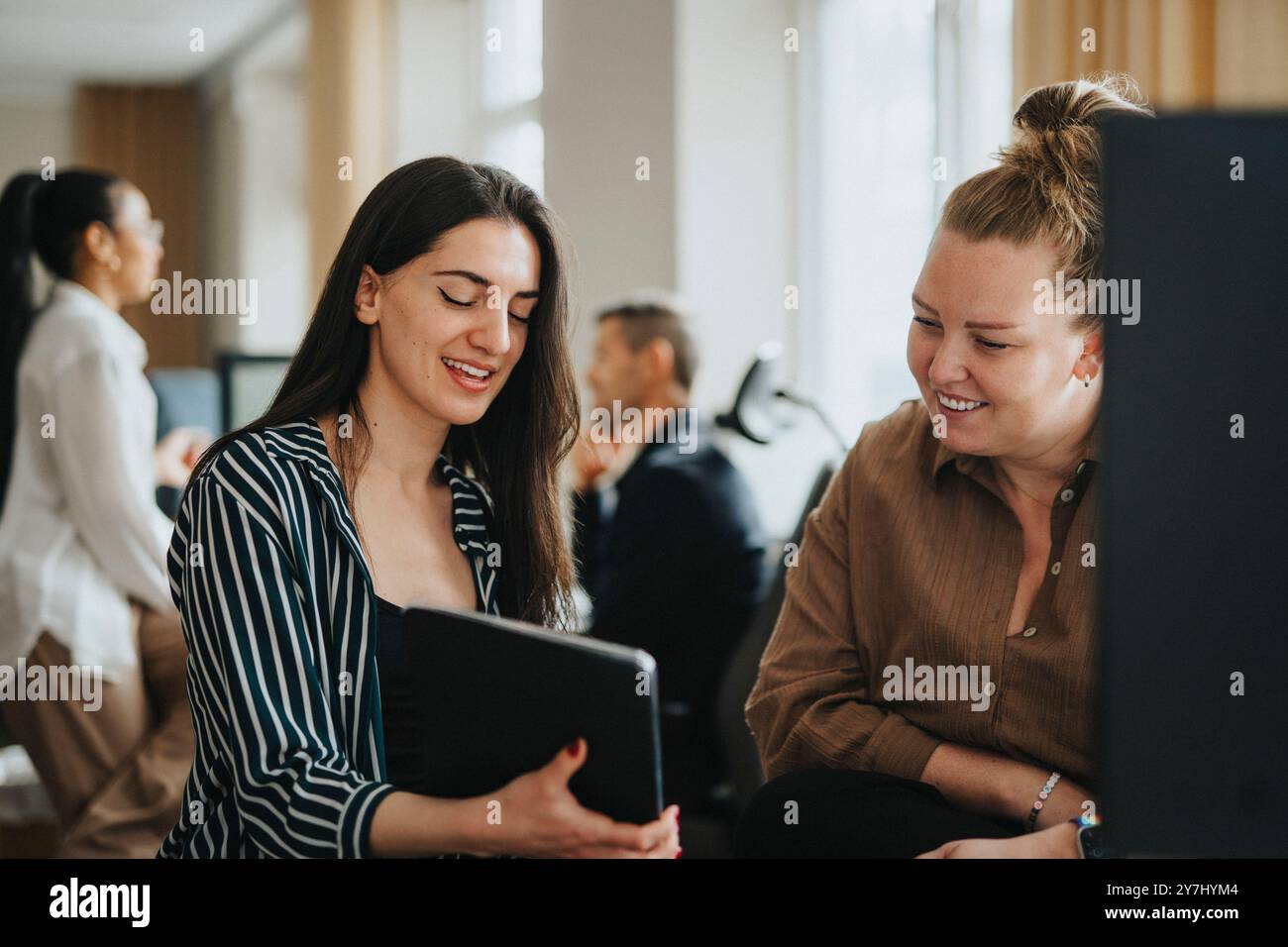 Female business professional sharing digital tablet with colleague at ...
