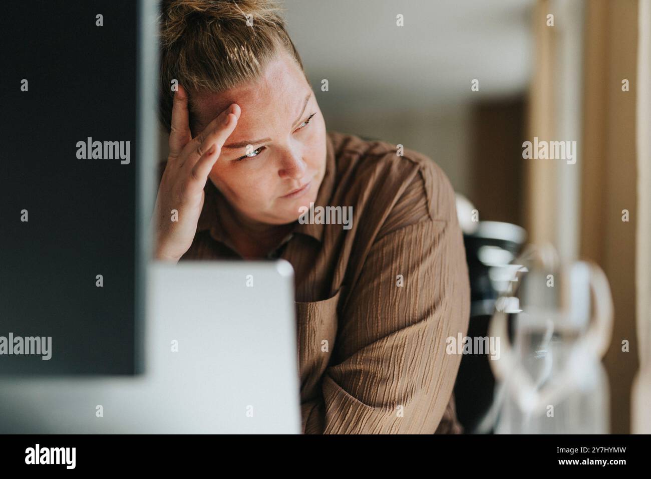 Tired female business professional touching forehead and looking ...