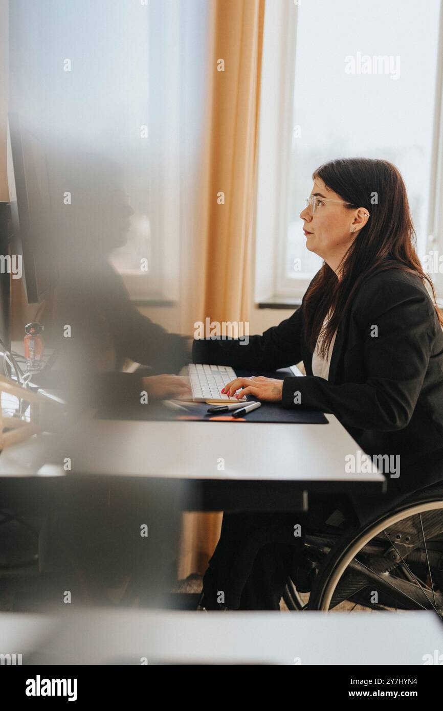 Side view of young businesswoman with physical disability working on ...