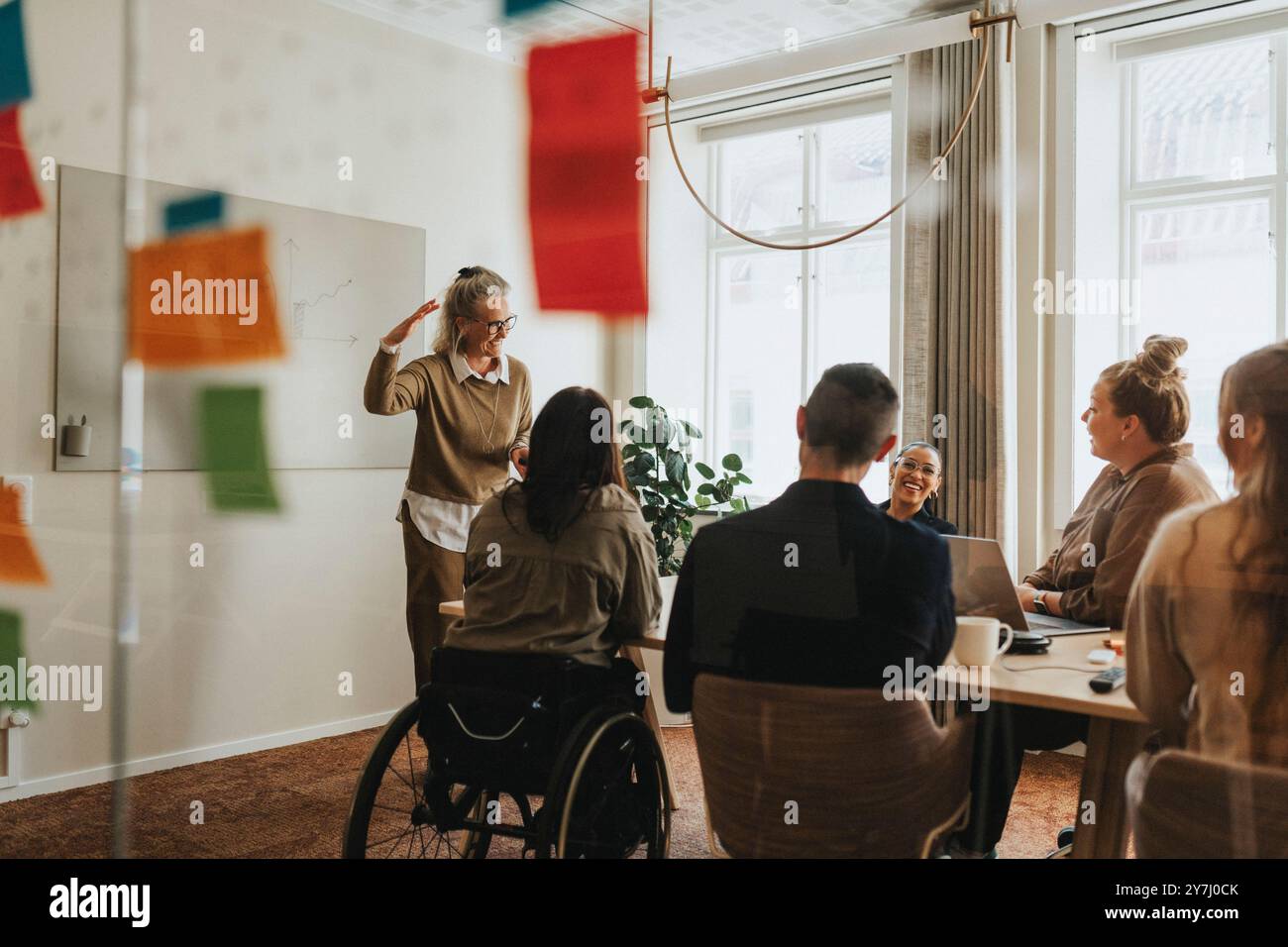 Happy female business professional explaining ideas to colleagues in ...