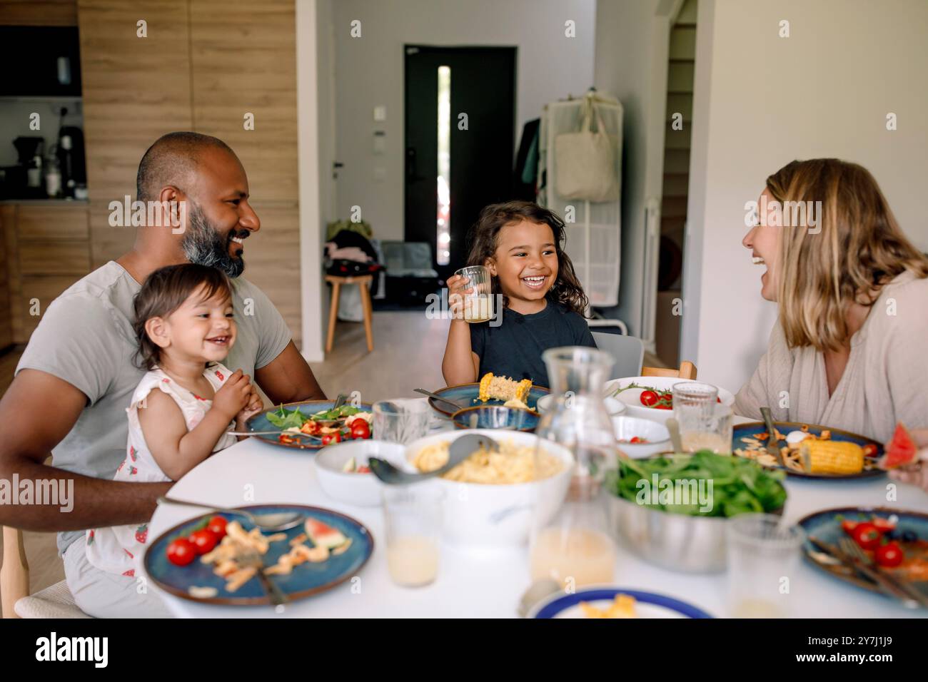 Happy family enjoying breakfast while sitting together on dining table ...