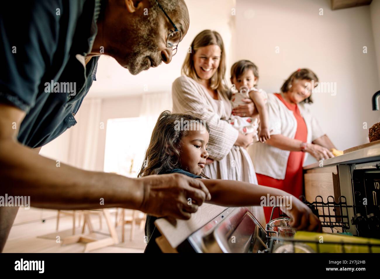 Boy loading utensils in dishwasher by grandfather at home Stock Photo ...