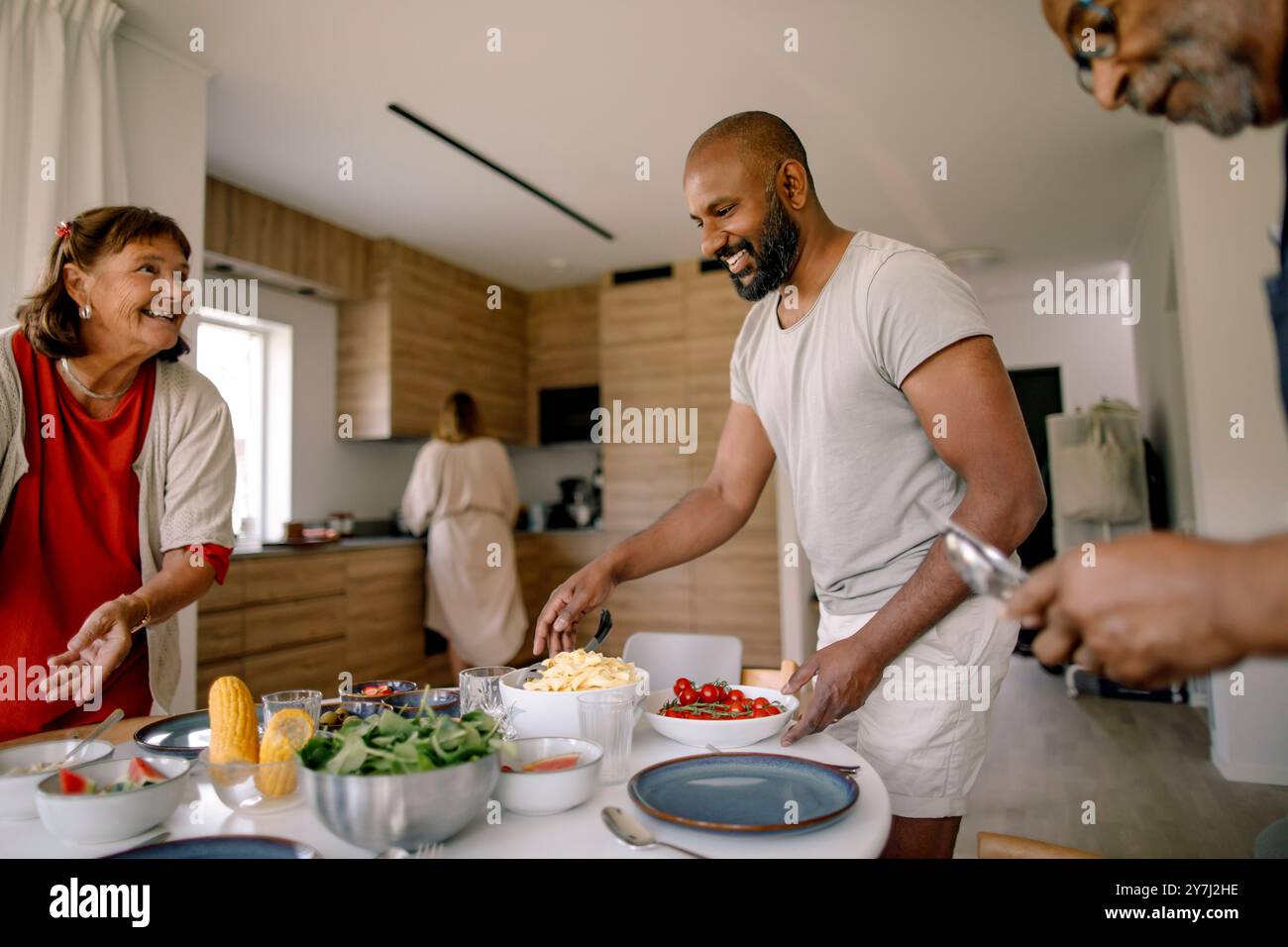 Happy family members helping each other in setting dining table for ...
