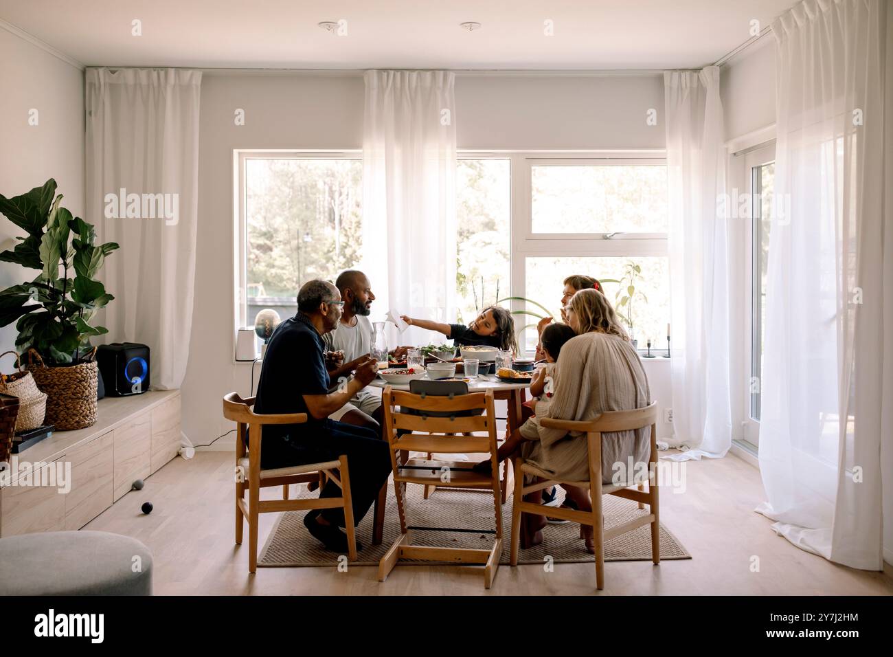 Happy multigenerational family having lunch while sitting together at ...