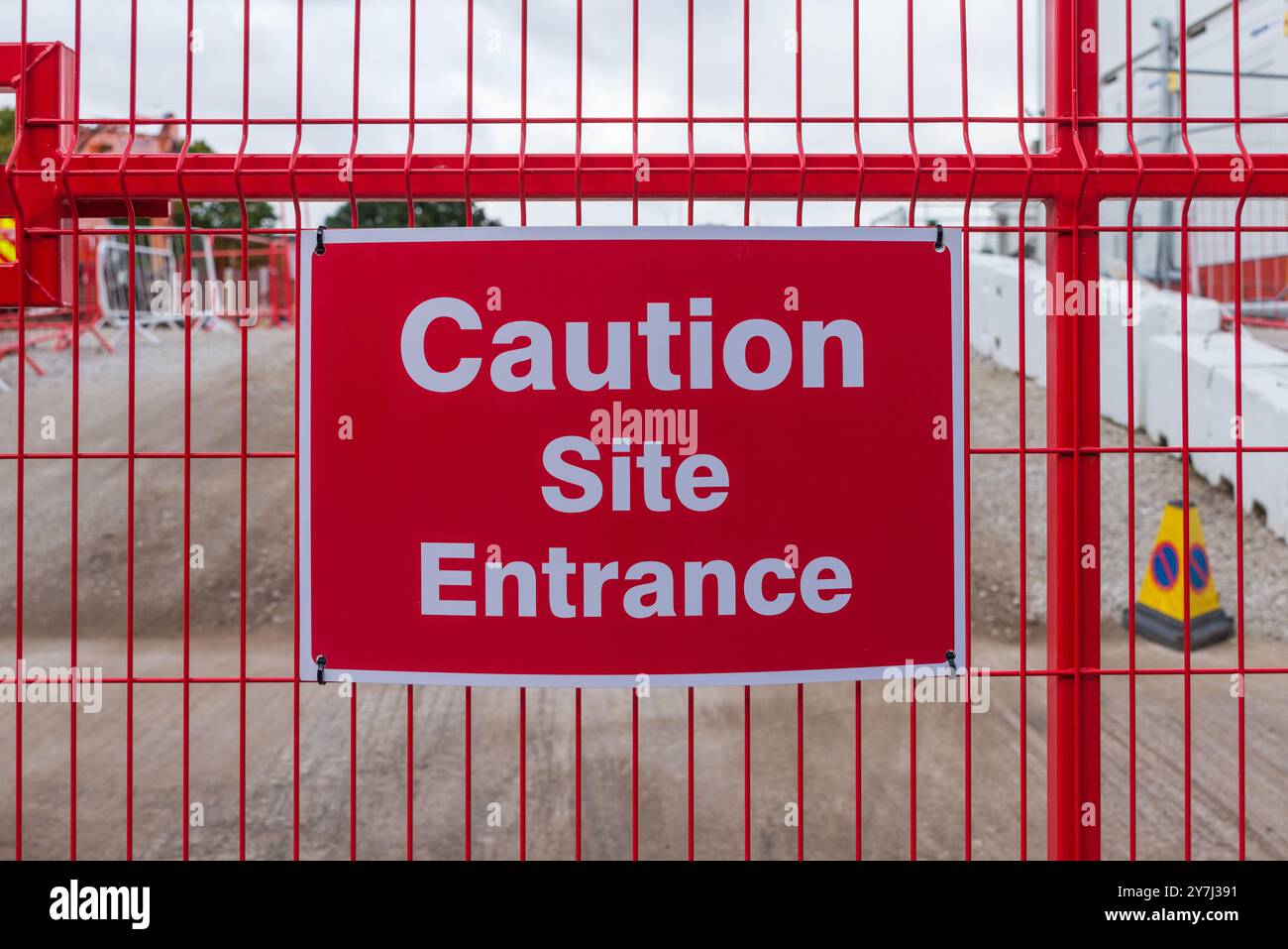 Warning sign on wire fence around building site saying caution site ...