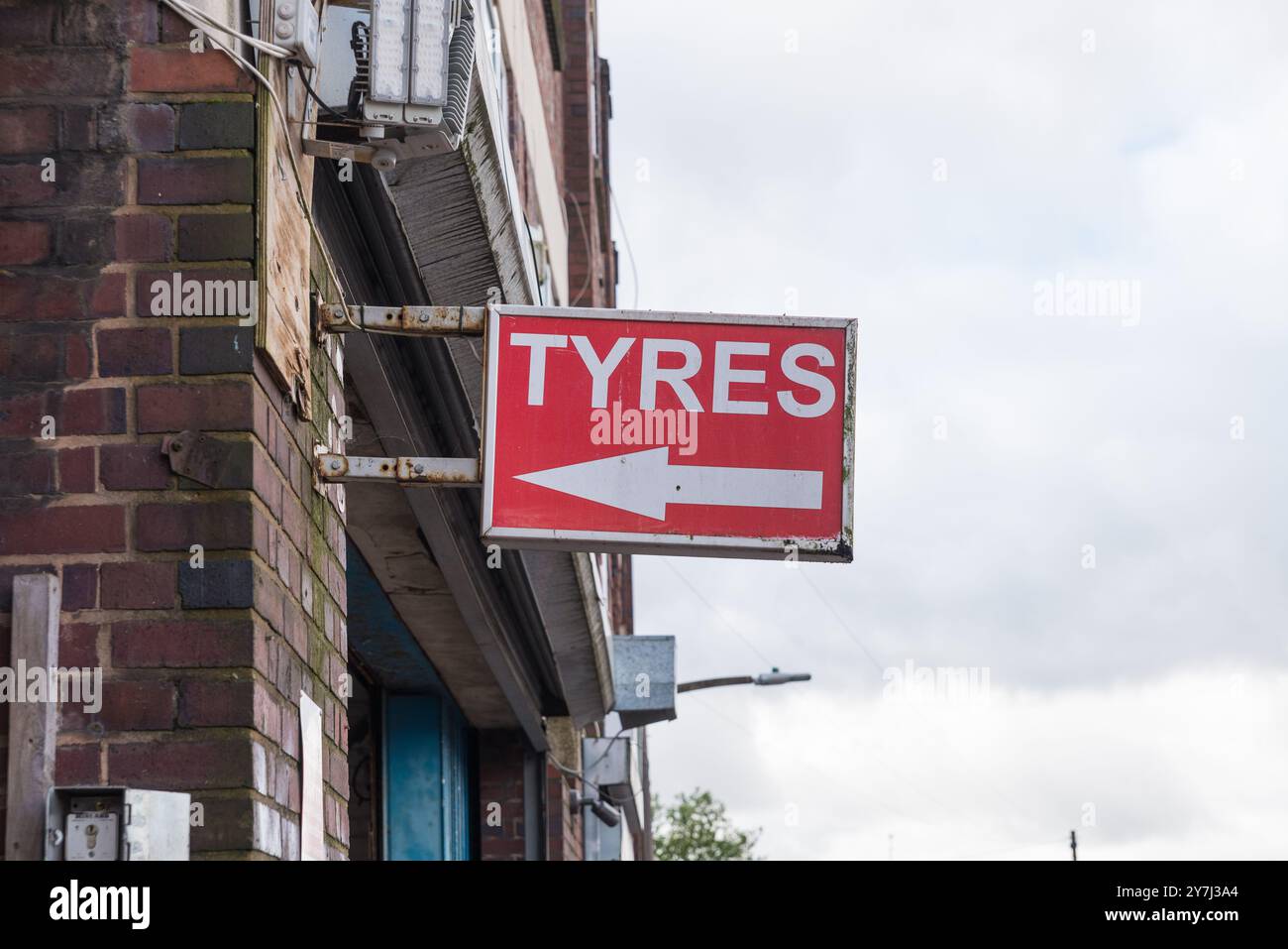 Red and white sign outside vehicle tyre depot saying tyres with arrow ...