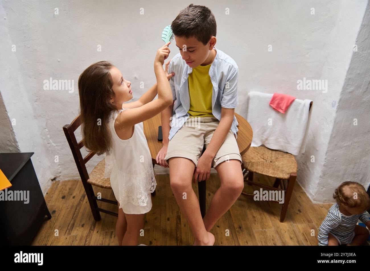 A girl playfully interacts with her older brother indoors, showcasing ...