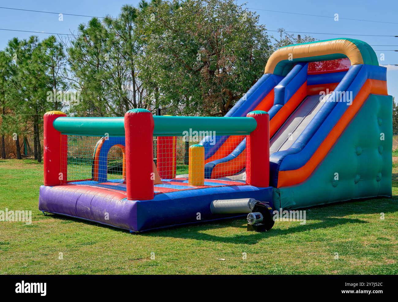 A colorful inflatable slide features for kids on the green grass with ...