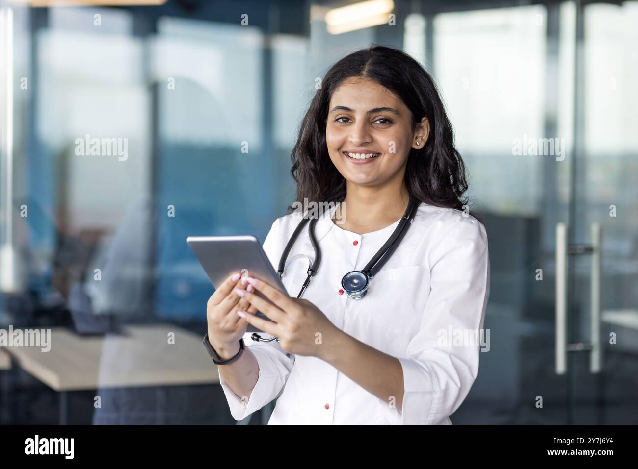 Young female doctor confidently using tablet with stethoscope in modern ...