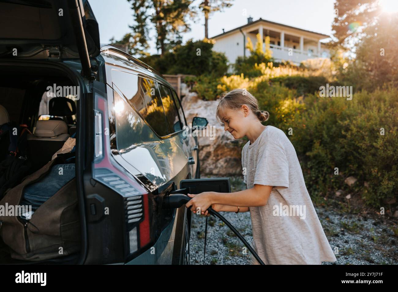 Boy inserting charging plug while standing near electric car Stock ...