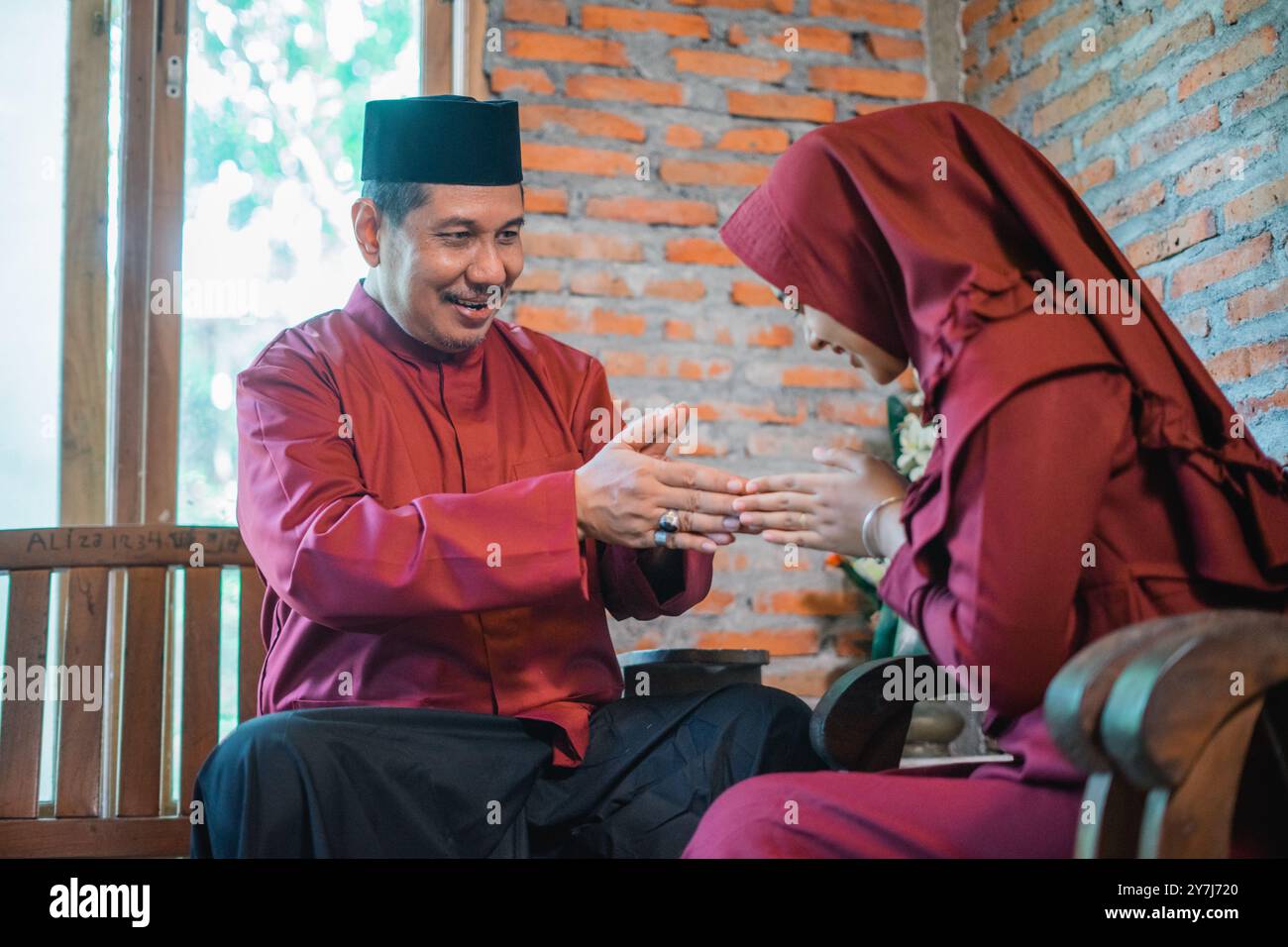 Asian Muslim husband makes hand gestures to wish wife a happy Eid Stock ...
