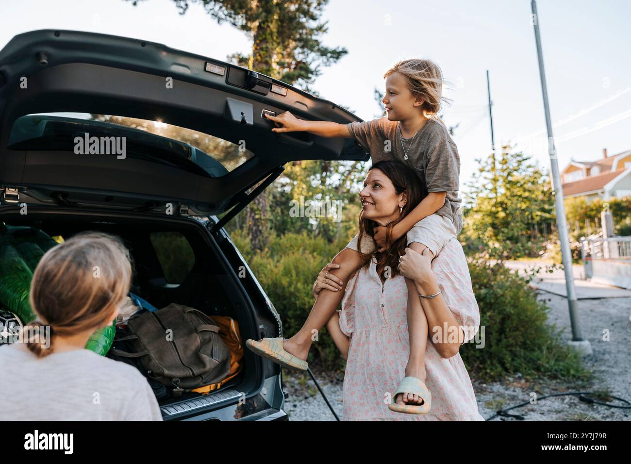 Son closing car trunk through push button while sitting on mother's ...