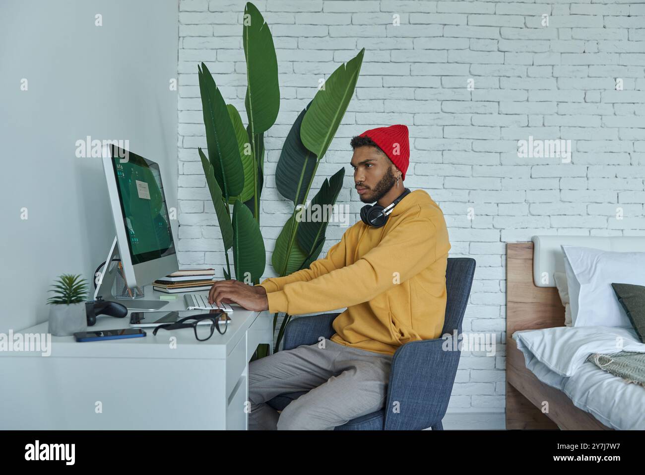 Concentrated young African man using computer while sitting at his ...