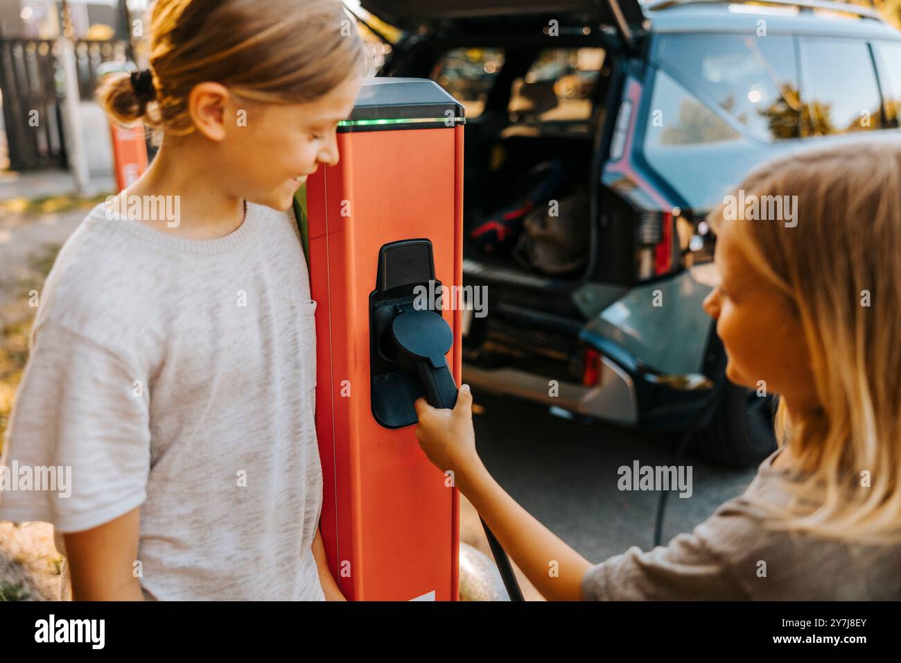 Boy removing charging plug with brother leaning on kiosk at station ...