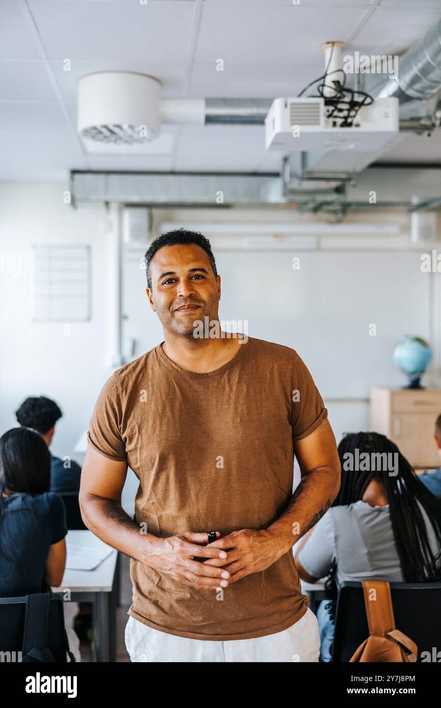 Portrait of smiling confident male professor standing in classroom at ...