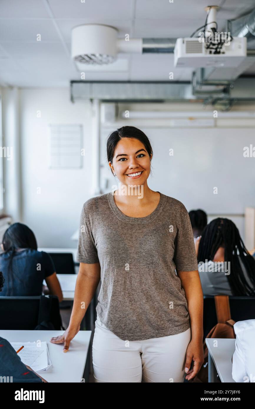 Portrait of happy female professor standing in classroom at junior high ...