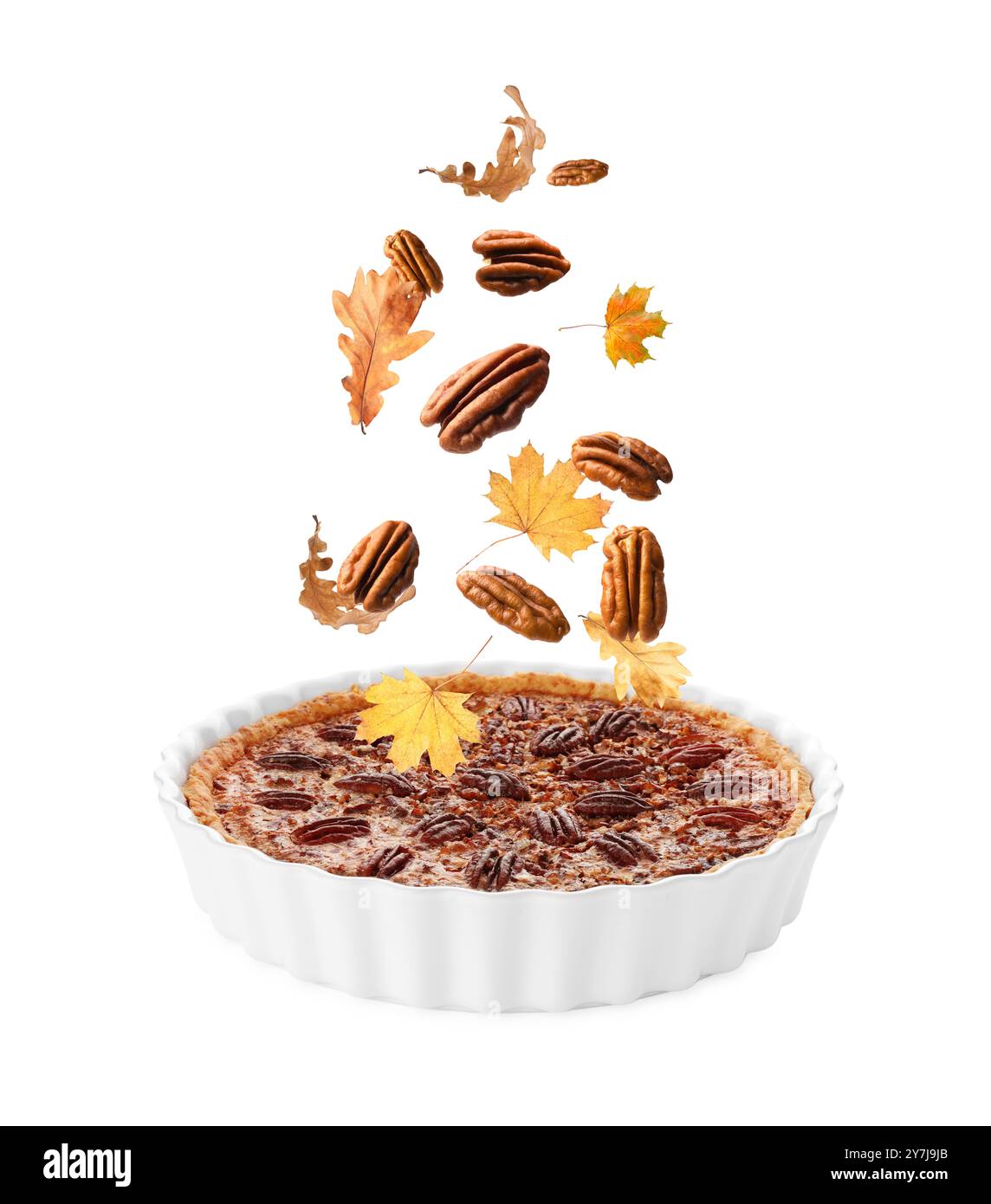 Autumn leaves and pecan nuts in air over fall cake on white background ...