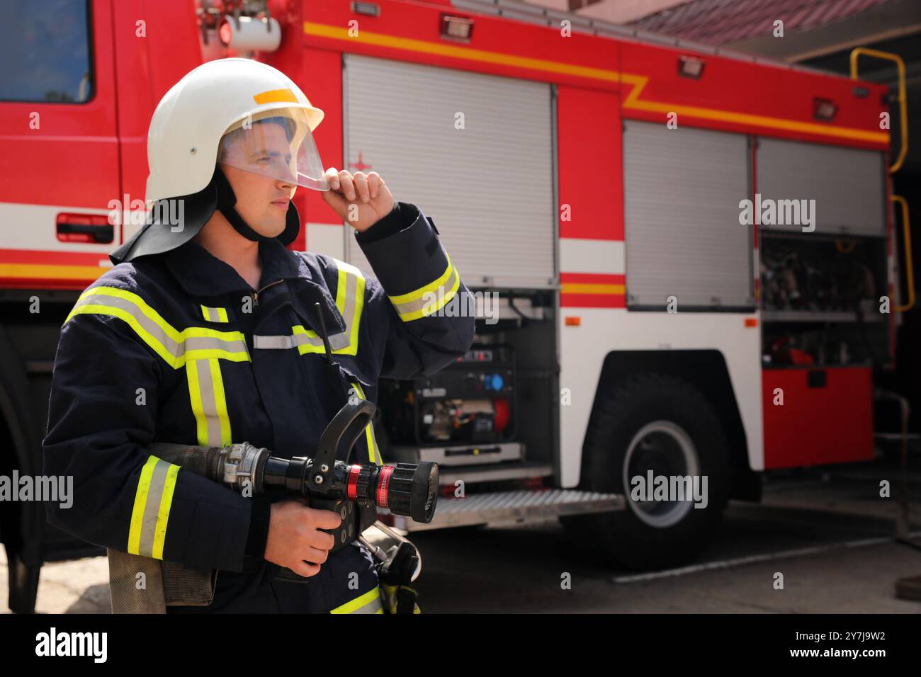 Firefighter in uniform with high pressure water jet near fire truck ...