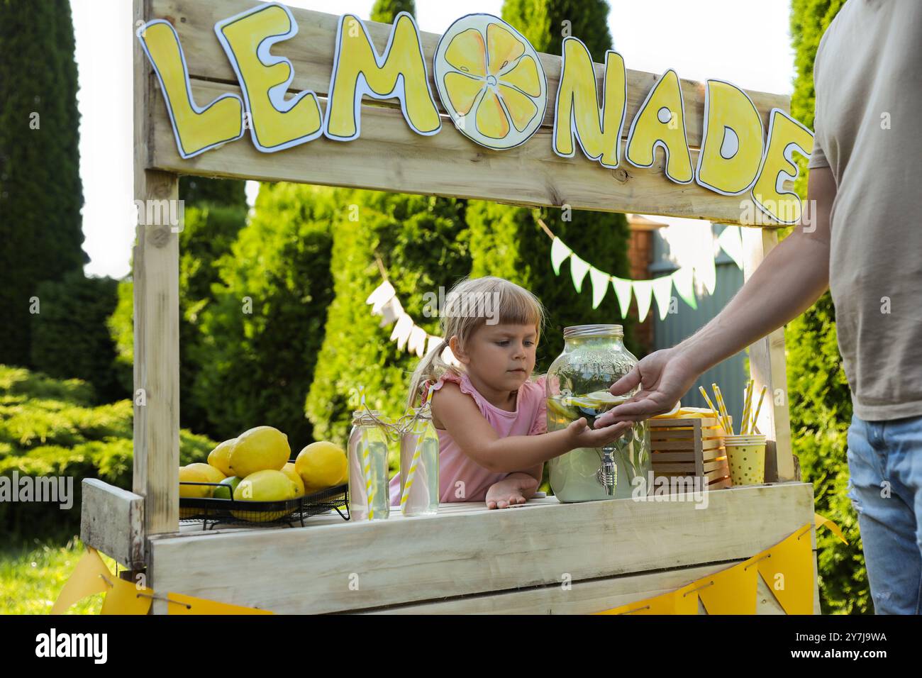 Cute little girl selling natural lemonade to man in park Stock Photo ...