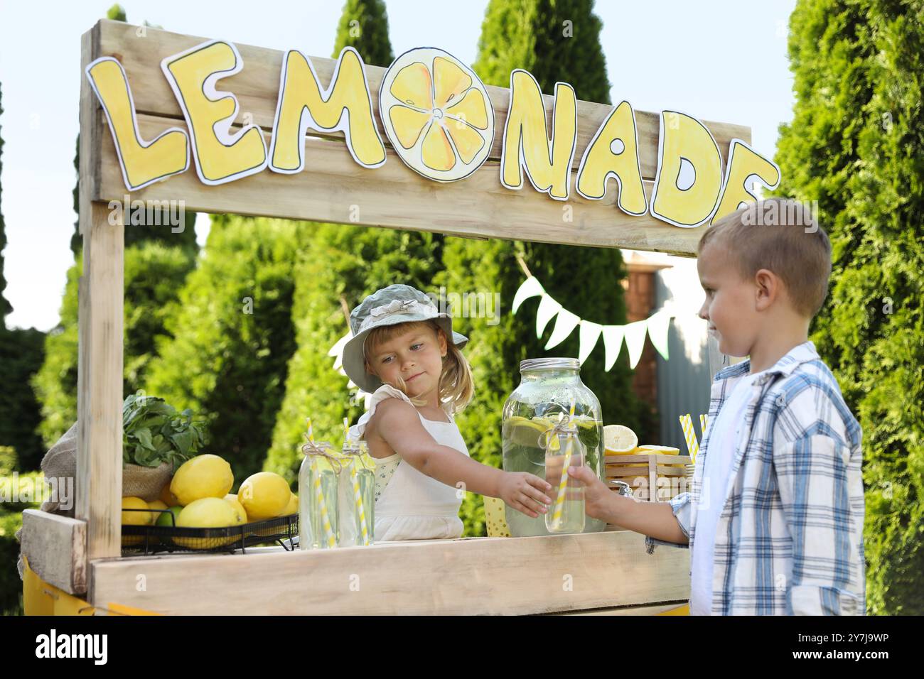 Cute little girl selling natural lemonade to boy in park Stock Photo ...
