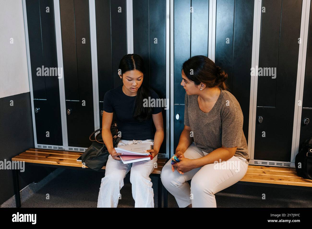 Female couch talking with teenage girl holding book while sitting on ...