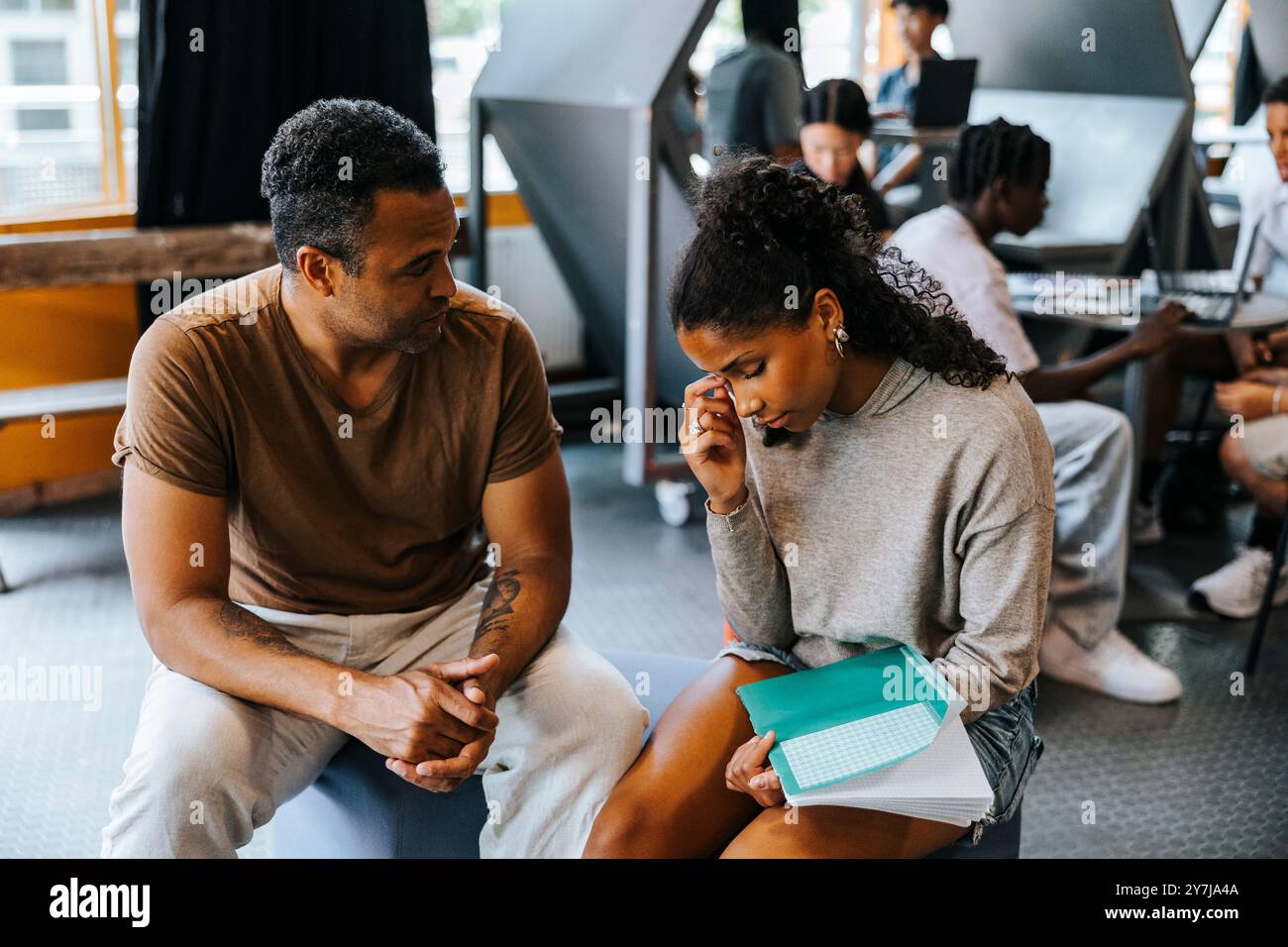 Male professor talking with stressed teenage girl while sitting in ...